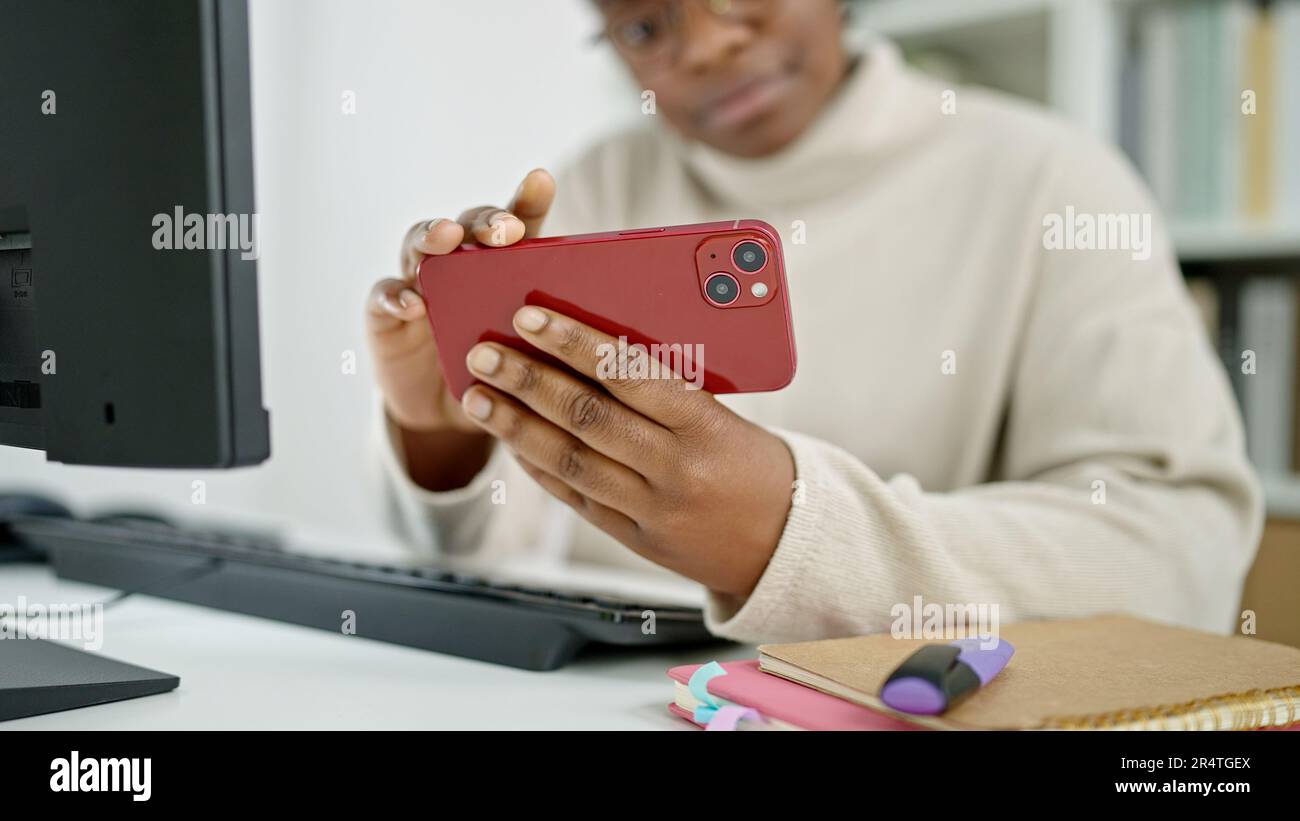 African american woman student using computer and smartphone at library ...