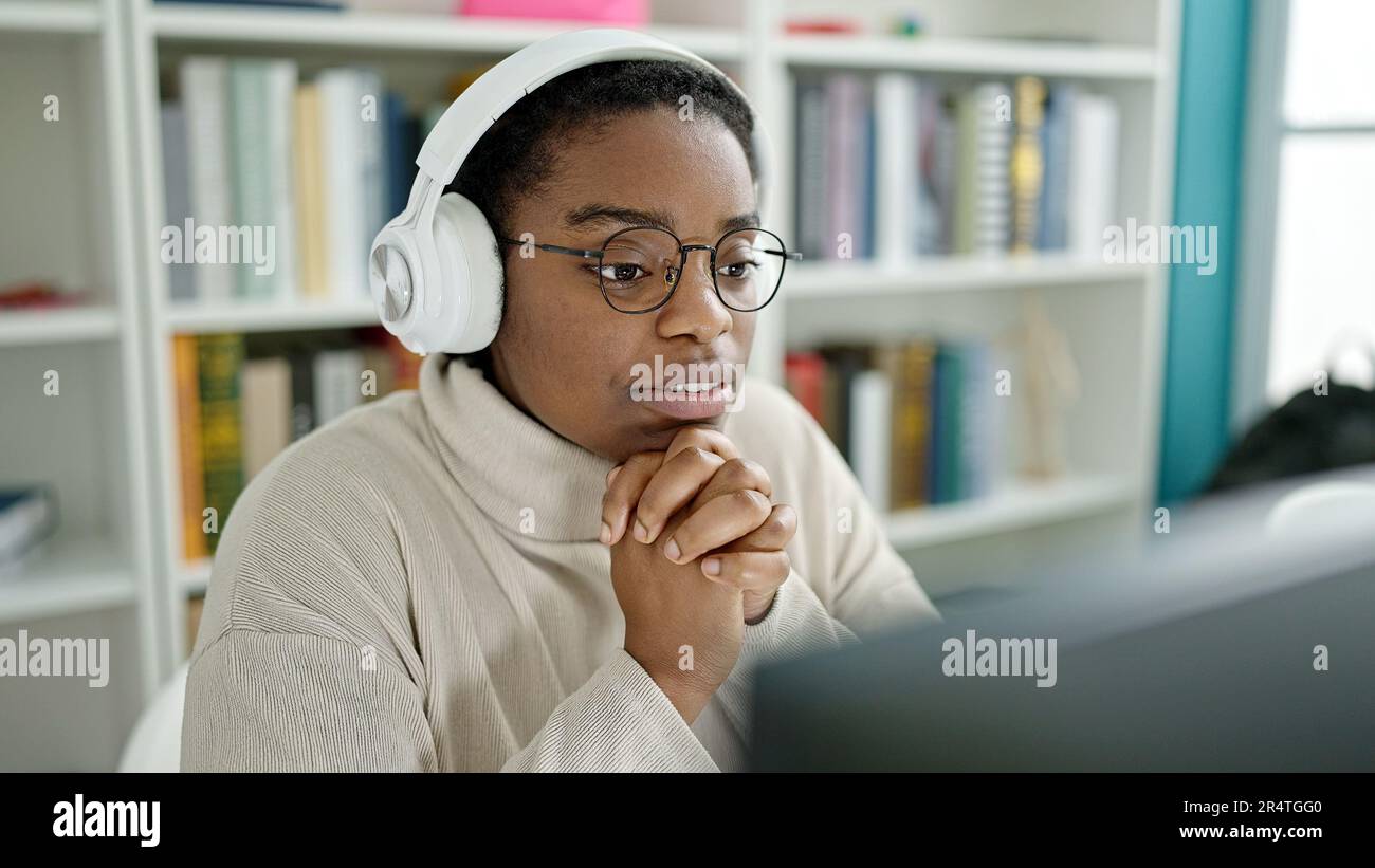 African american woman student using computer and headphones studying ...