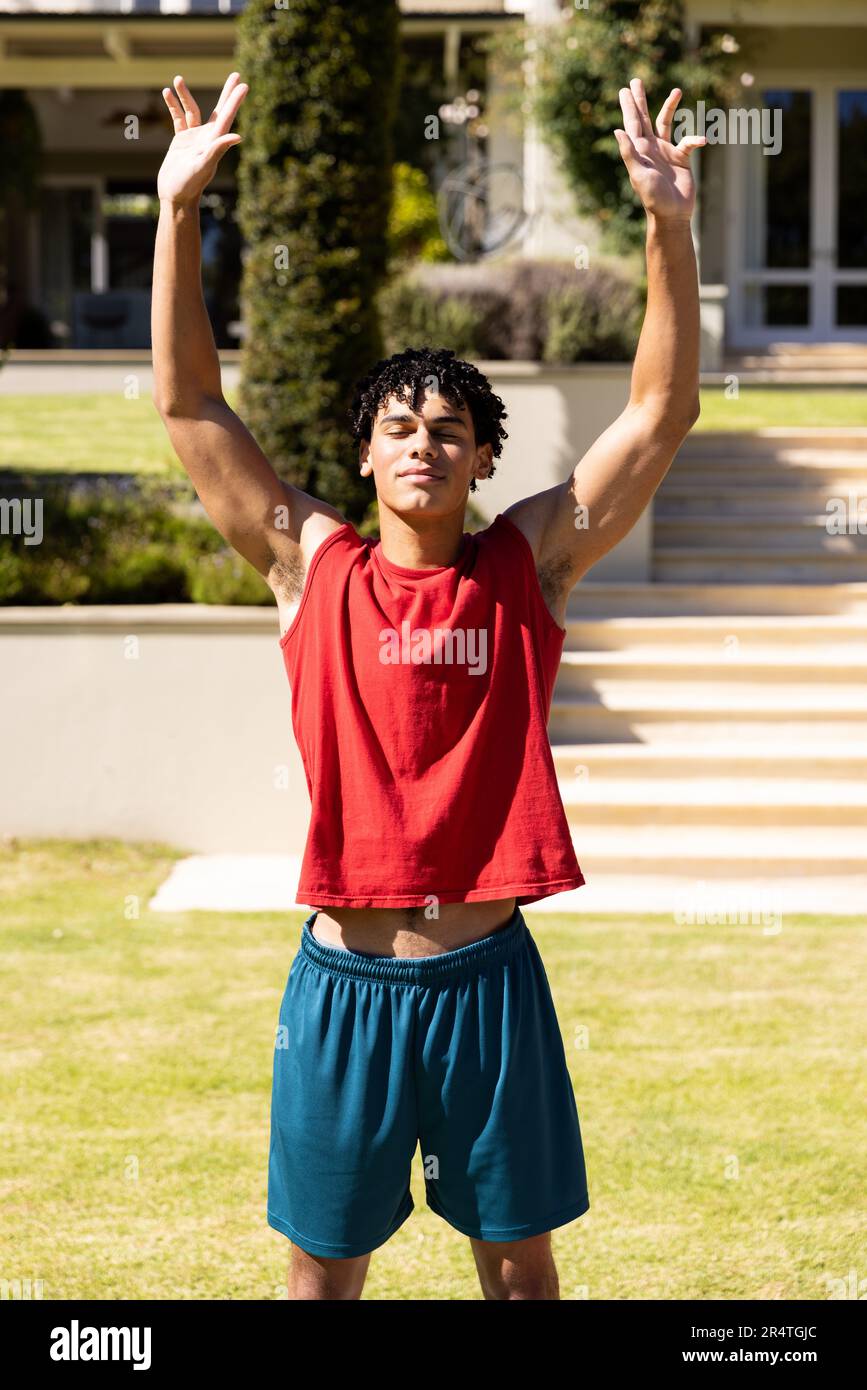 Biracial handsome young man with eyes closed and arms raised meditating ...