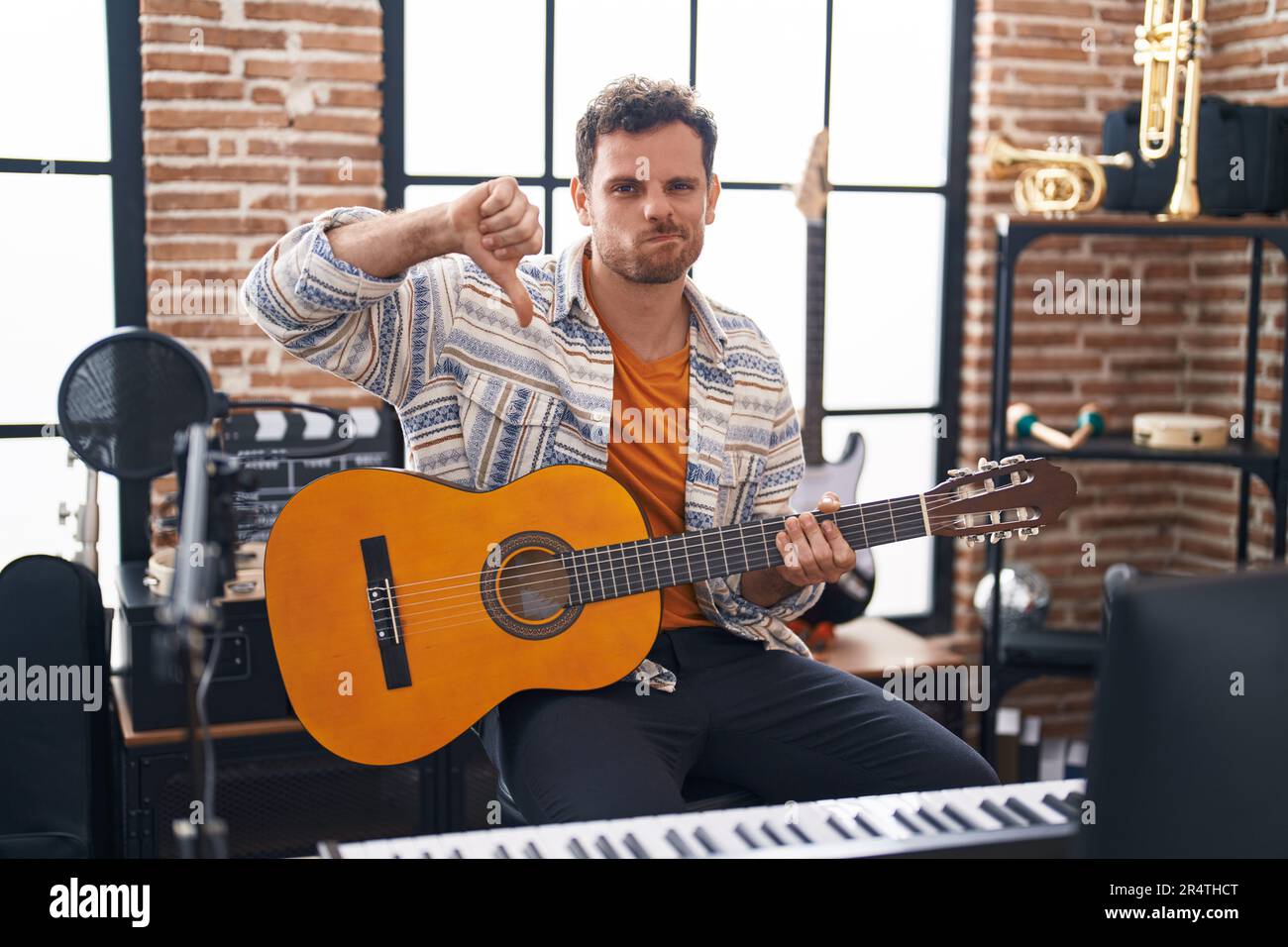 Young hispanic man playing classic guitar at music studio with angry ...