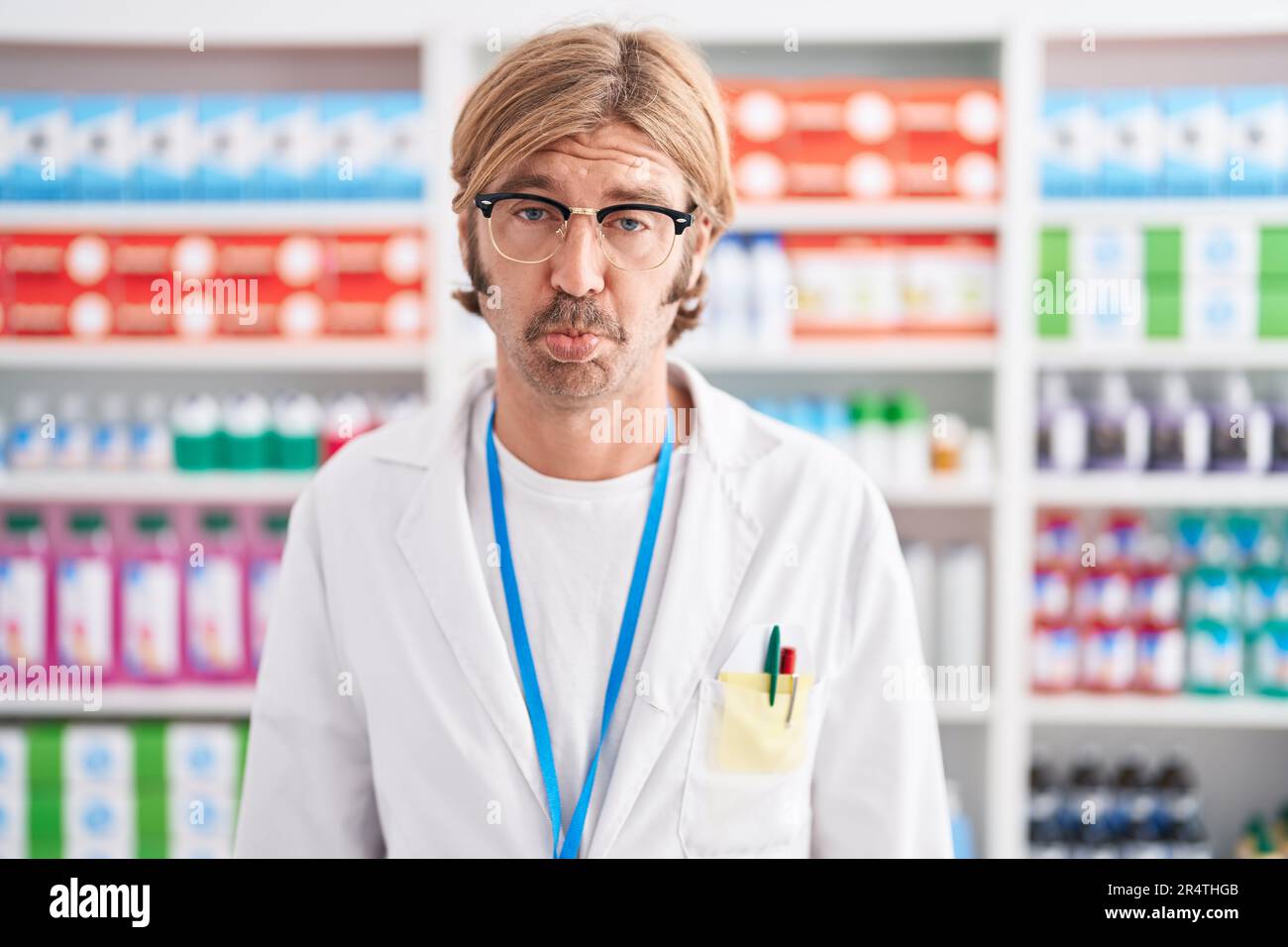 Caucasian man with mustache working at pharmacy drugstore depressed and ...