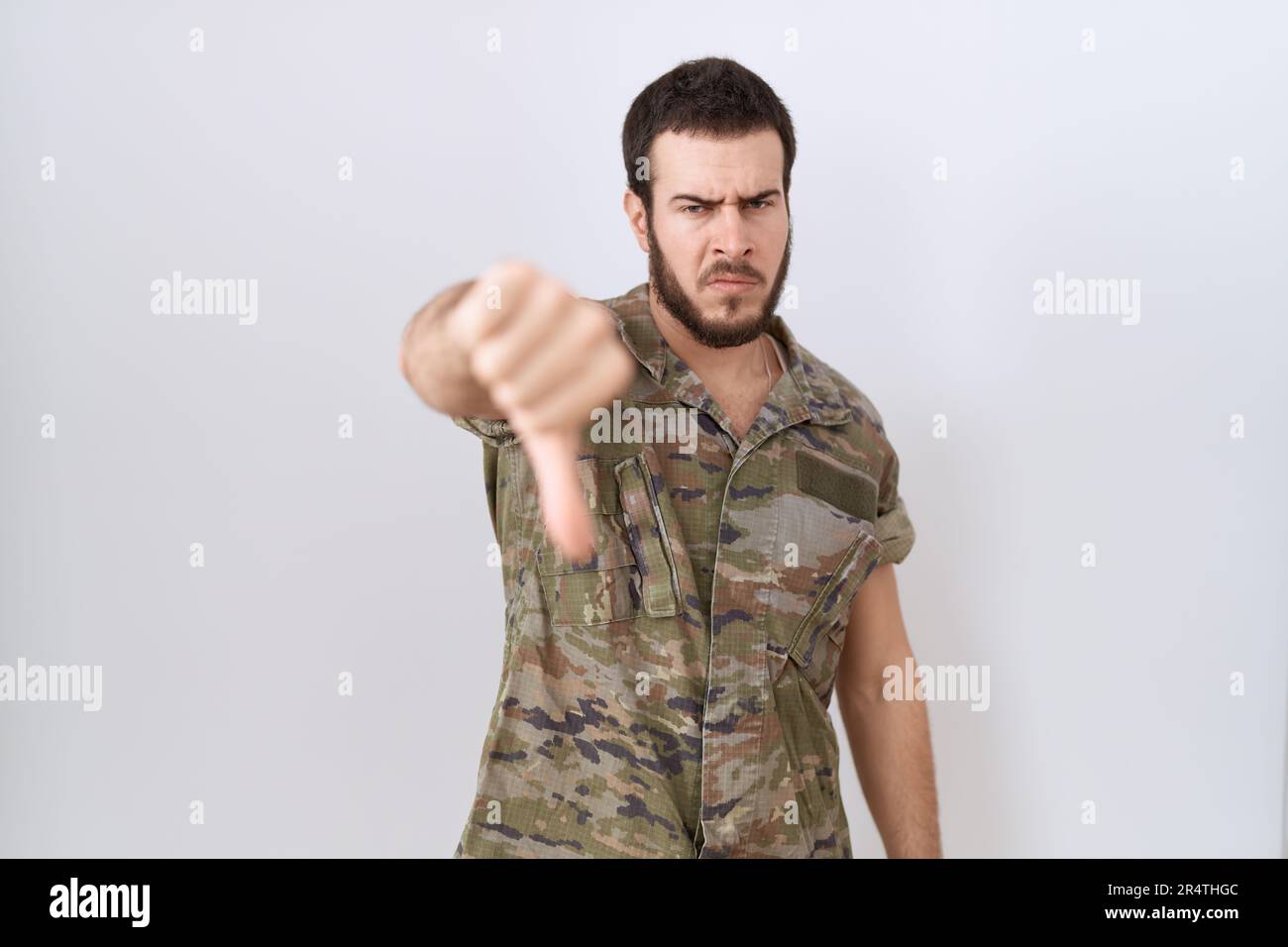Young hispanic man wearing camouflage army uniform looking unhappy and ...