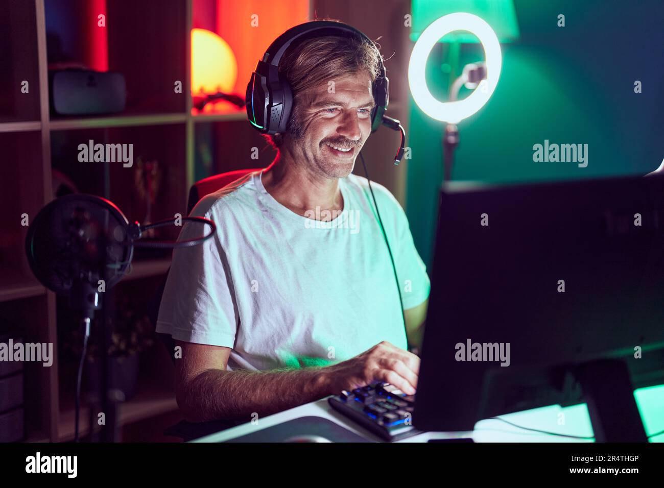 Young blond man streamer playing video game using computer at gaming ...