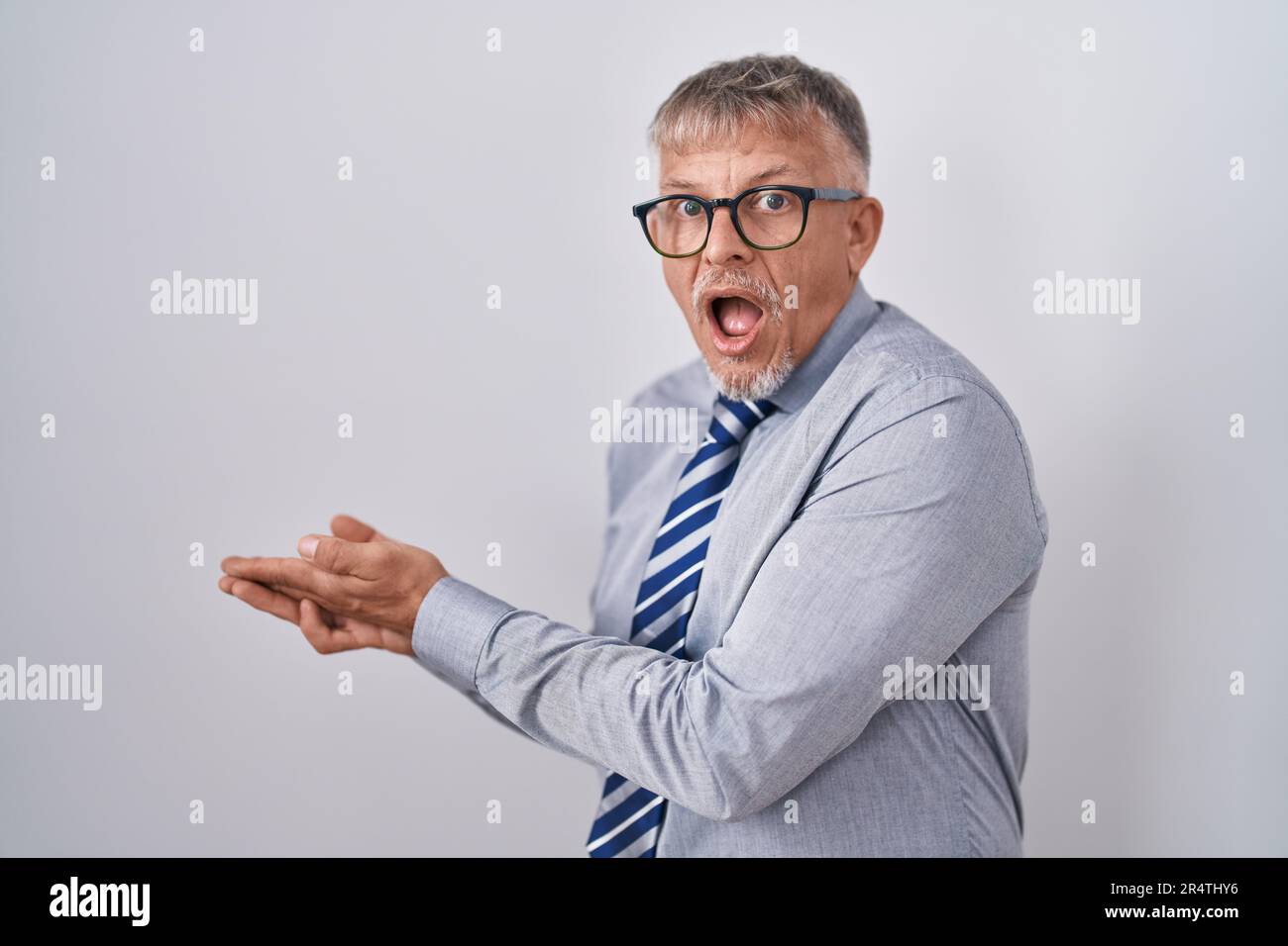 Hispanic business man with grey hair wearing glasses pointing aside ...