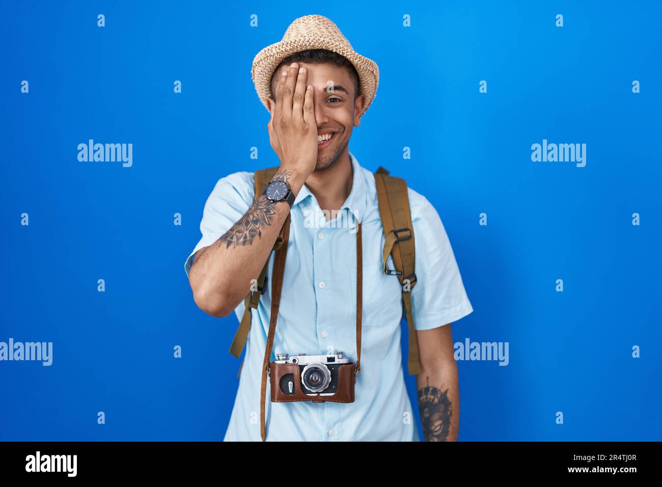 Brazilian young man holding vintage camera covering one eye with hand ...