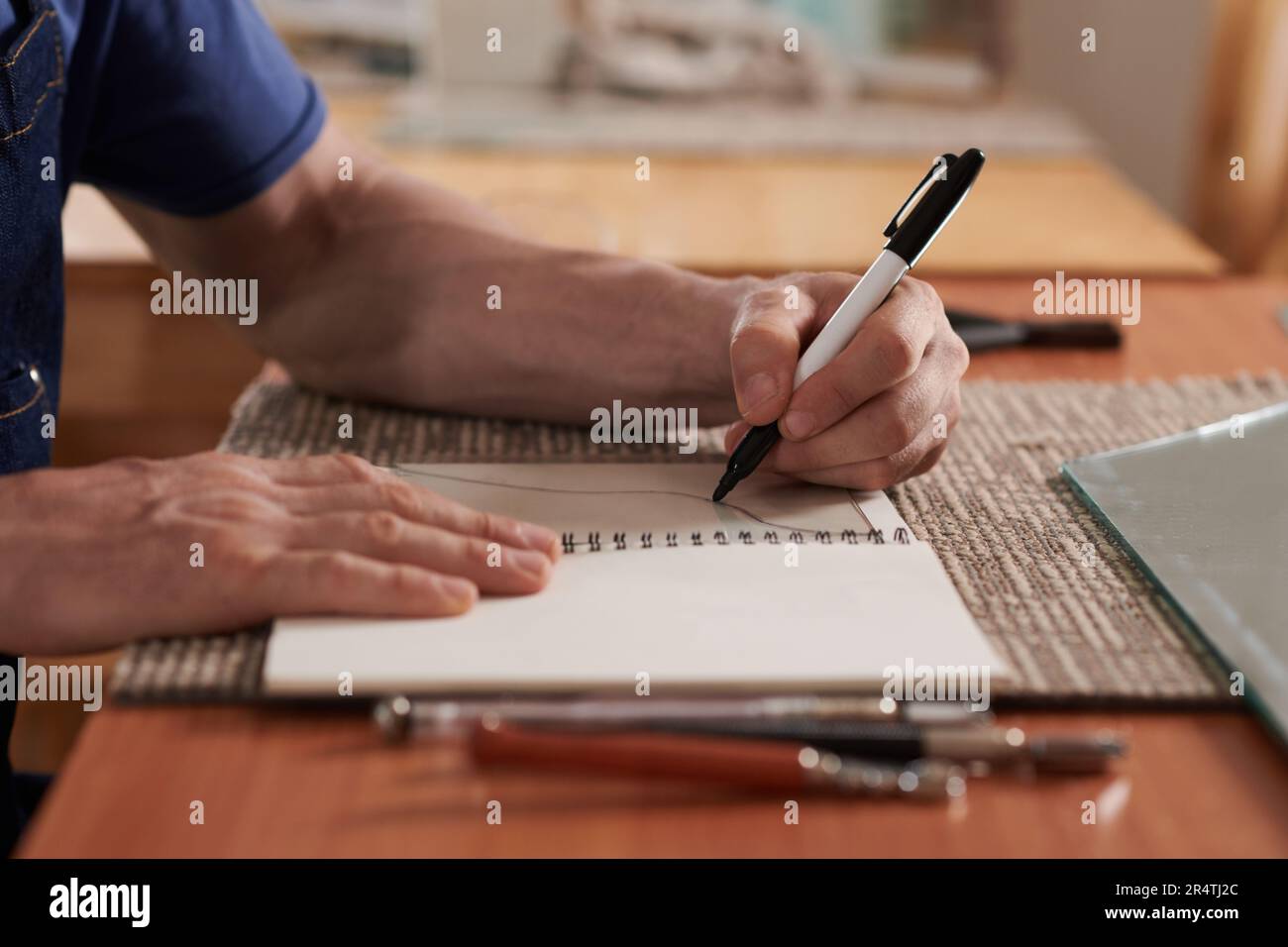 Glass worker drawing wavy line in notepad when working on sketches for ...