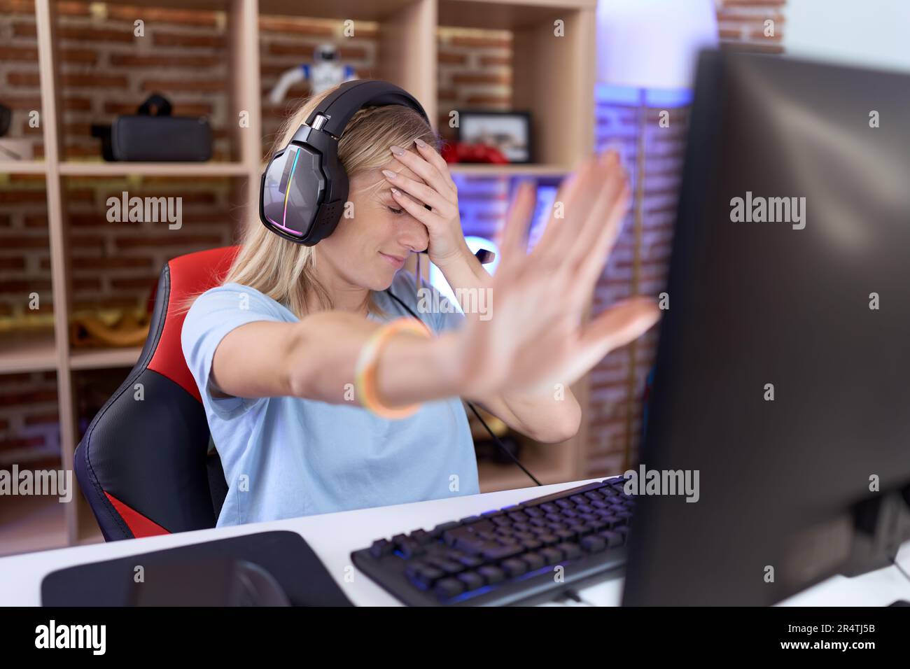 Young caucasian woman playing video games wearing headphones covering ...