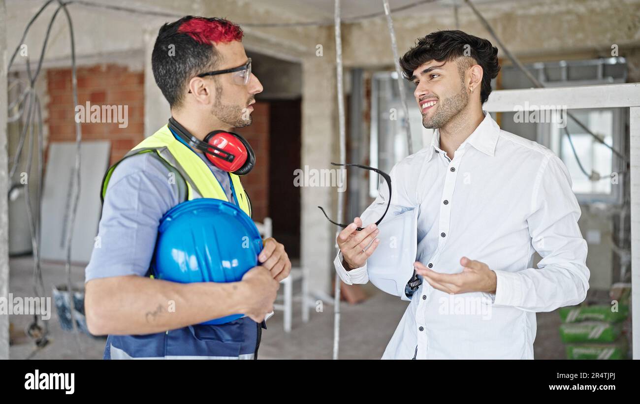 Two men builder and architect standing together speaking at ...