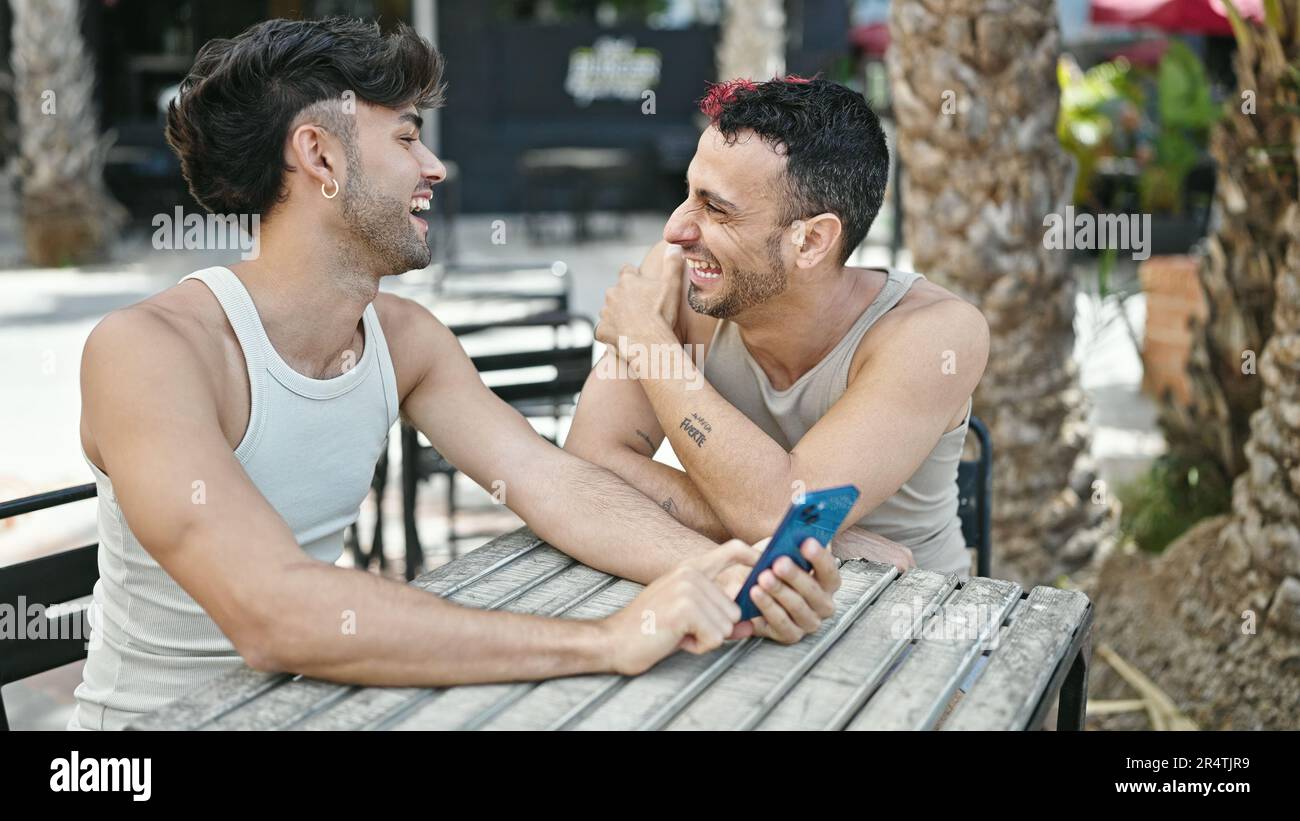 Two men couple smiling confident using smartphone at coffee shop terrace Stock Photo - Alamy