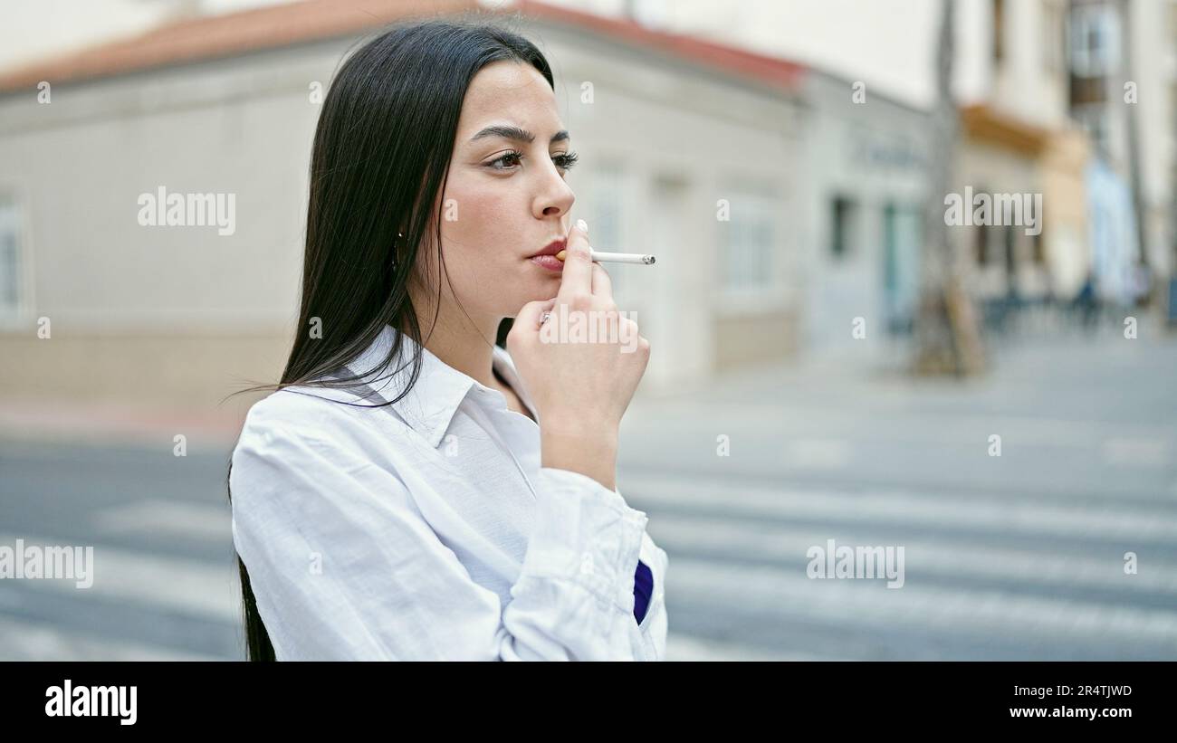 Young beautiful hispanic woman smoking at street Stock Photo - Alamy
