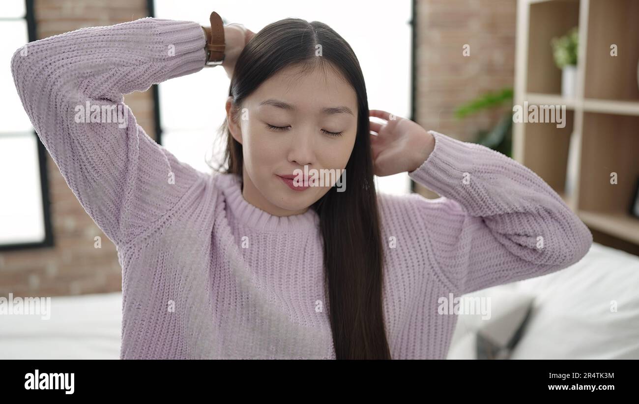 Young chinese woman waking up stretching arms at bedroom Stock Photo ...