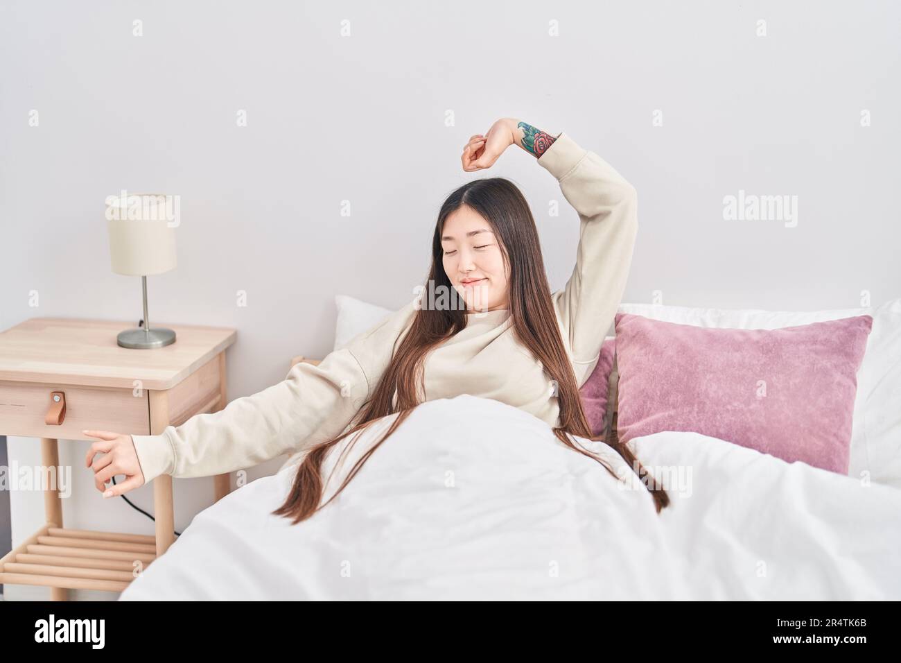 Chinese woman waking up stretching arms at bedroom Stock Photo - Alamy