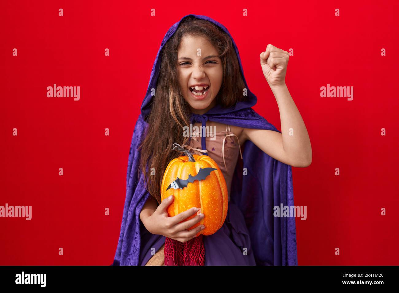 Little hispanic girl wearing witch halloween costume annoyed and ...