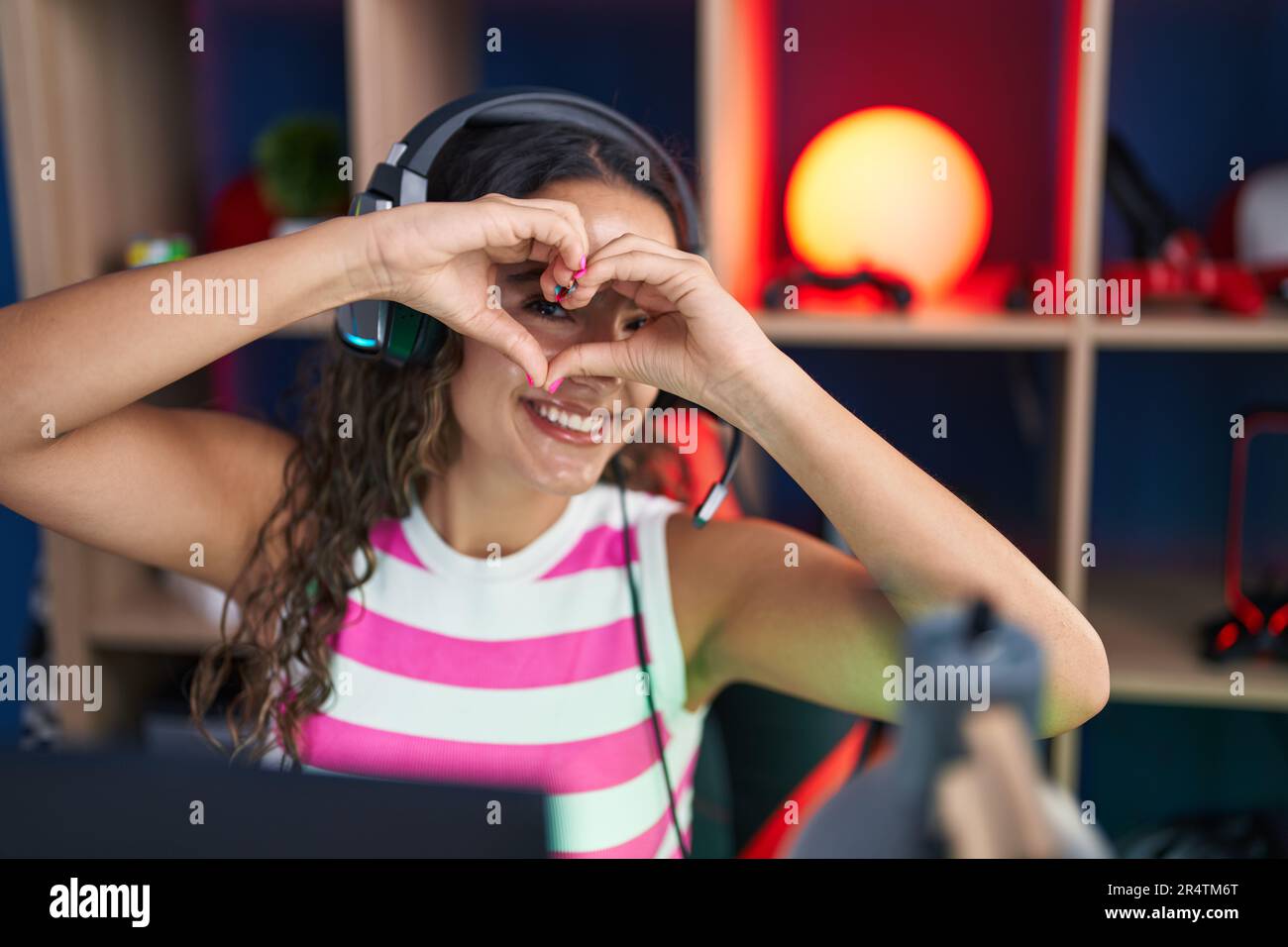 Young beautiful hispanic woman streamer smiling confident doing heart ...
