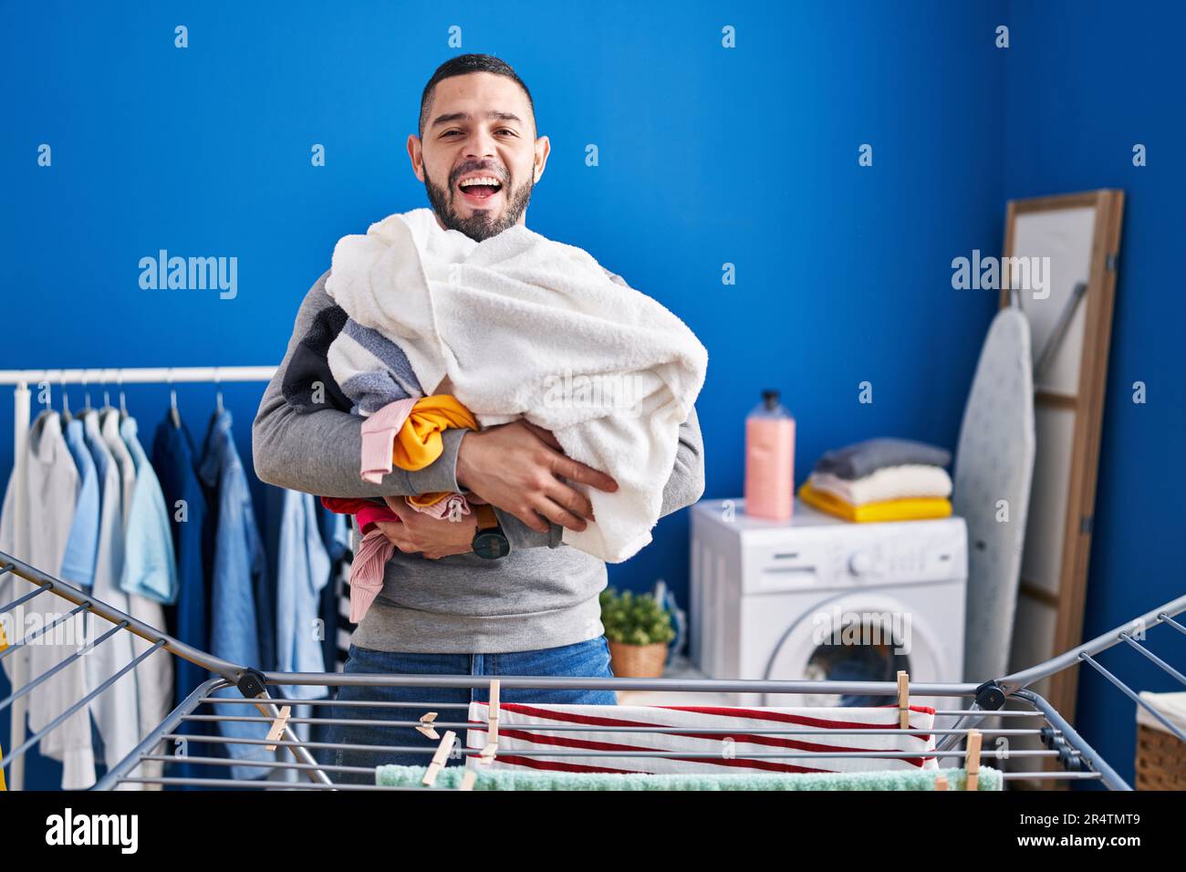 Hispanic man hanging clothes at clothesline smiling and laughing hard ...
