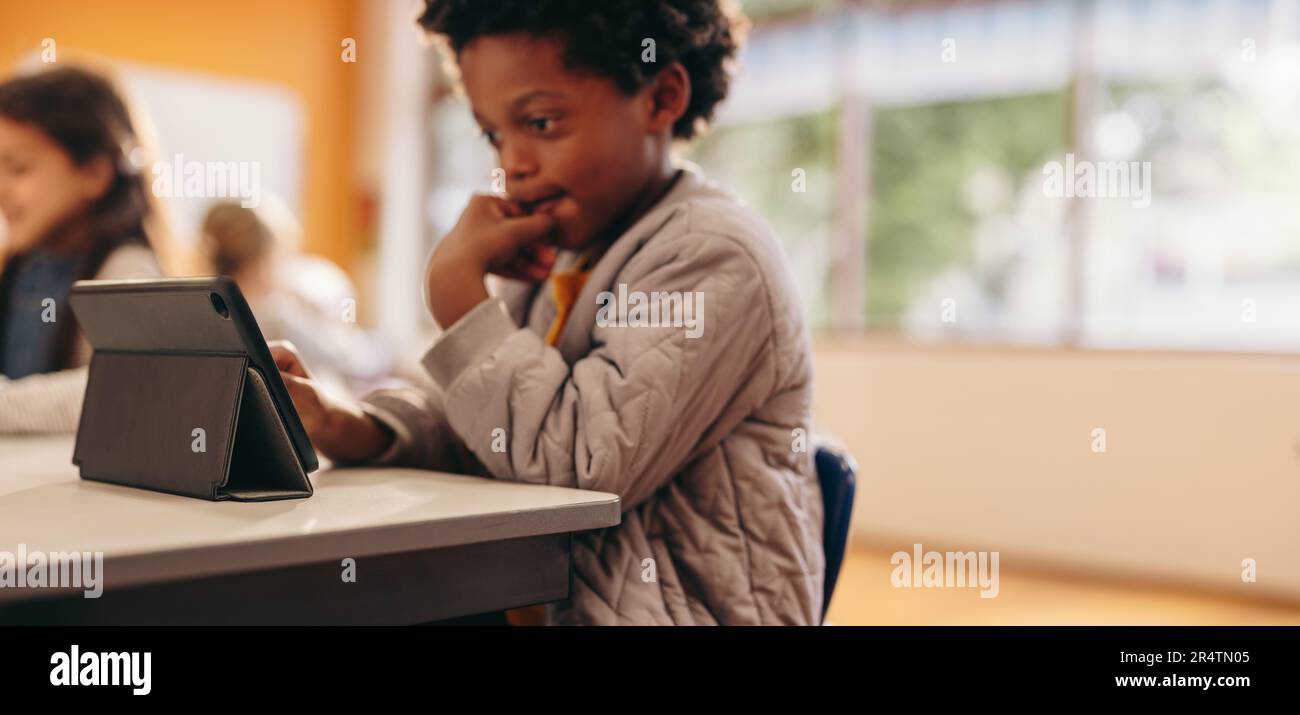 Little boy learning to code using a tablet. Male student thinking as he ...