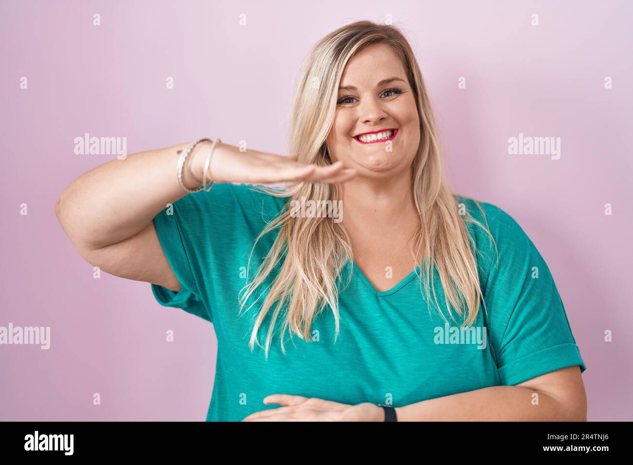Caucasian plus size woman standing over pink background gesturing with ...