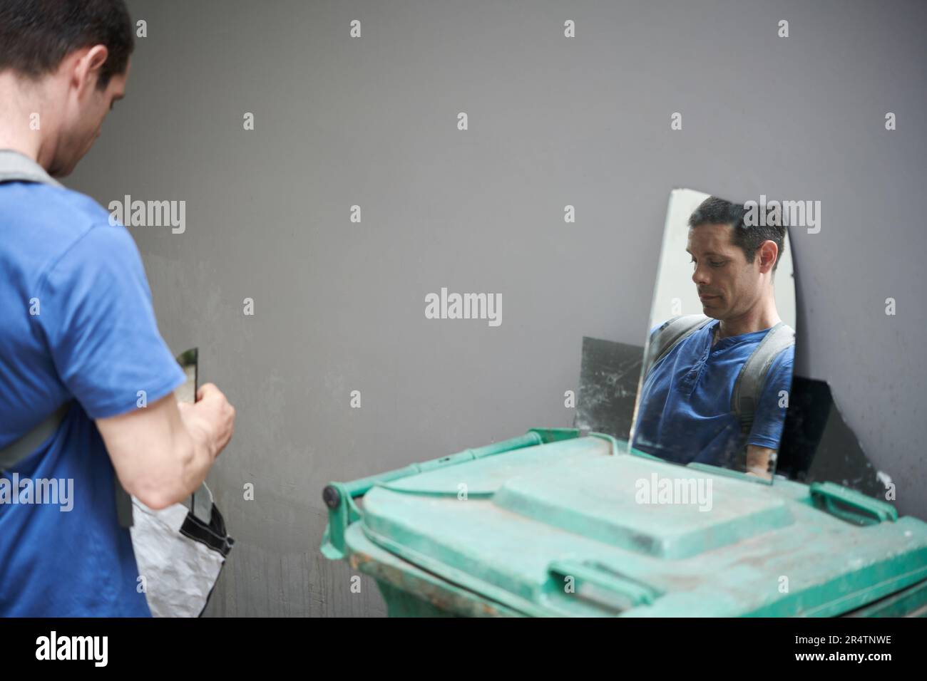 Reflection of artist collecting broken glass and mirror pieces for ...