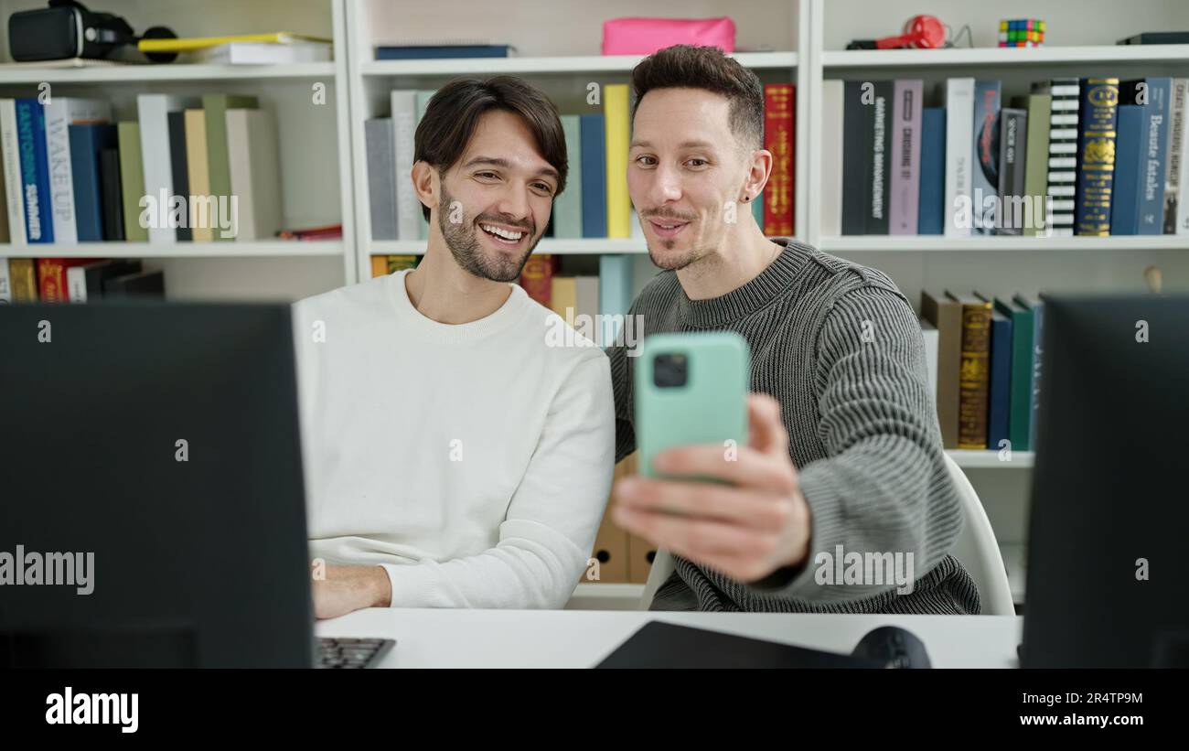 Two men students using computer and smartphone at library university ...
