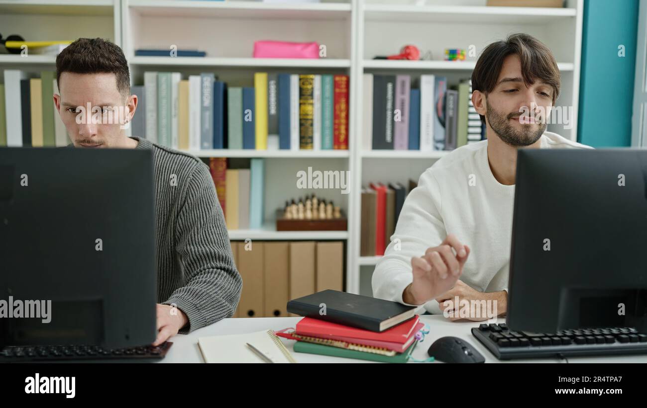 Two men students using computer studying at library university Stock Photo - Alamy