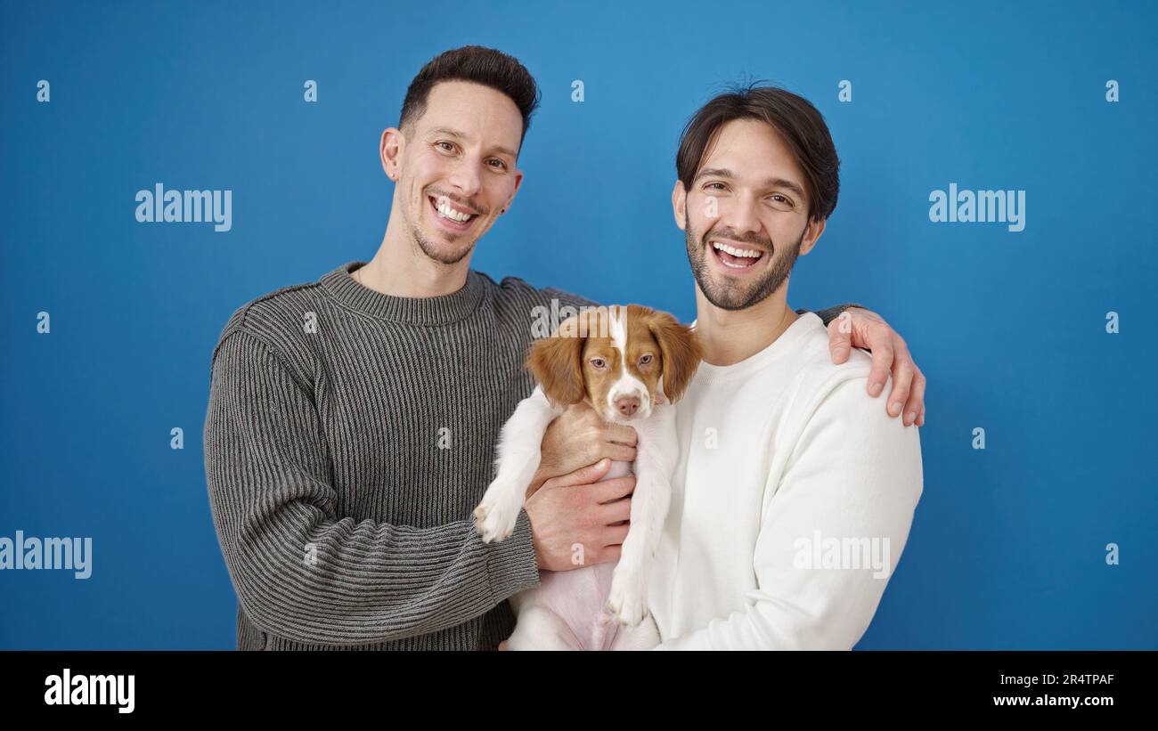 Two men couple smiling confident standing hugging dog over isolated ...