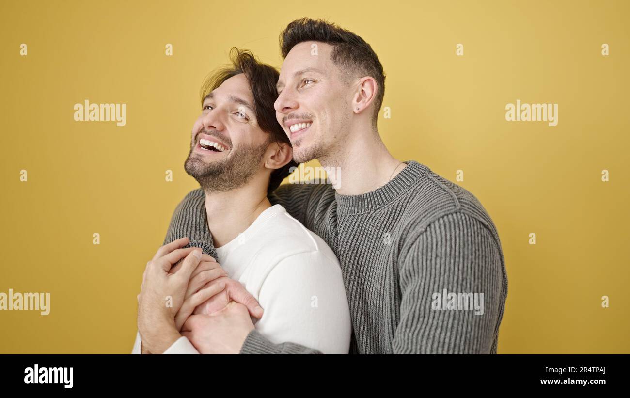 Two men couple hugging each other standing over isolated yellow ...