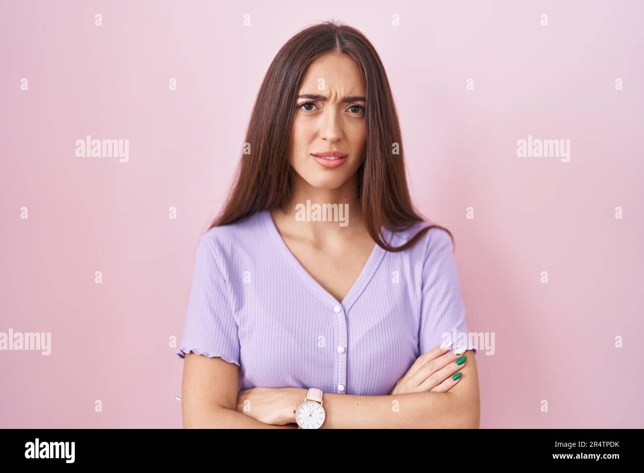 Young hispanic woman with long hair standing over pink background ...