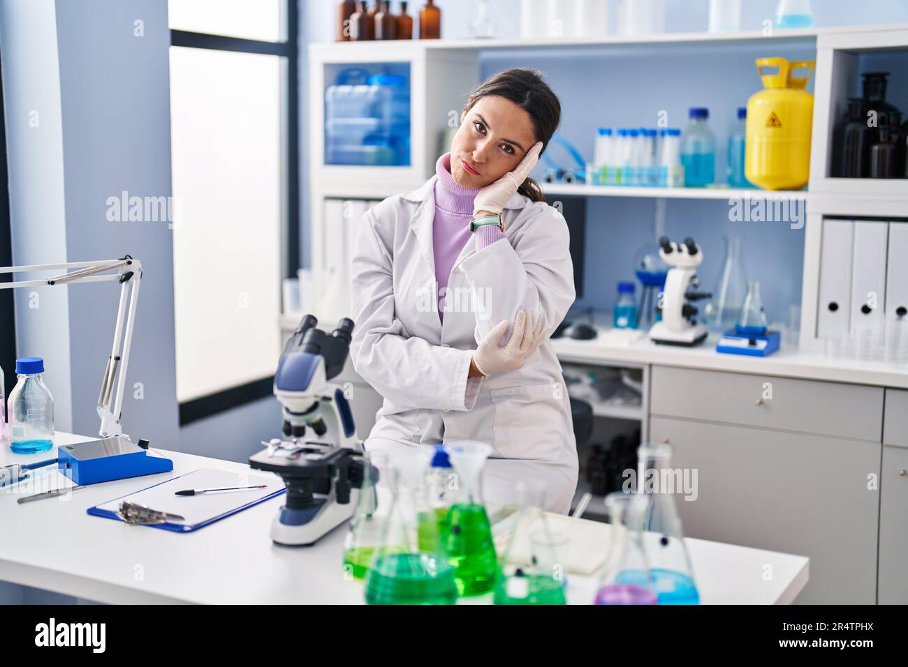 Young brunette woman working at scientist laboratory thinking looking ...