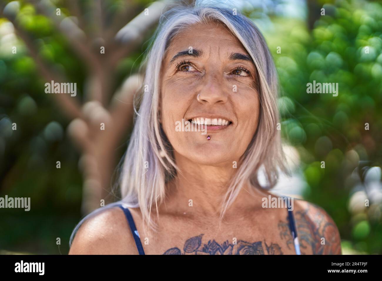 Middle age grey-haired woman smiling confident looking to the side at ...