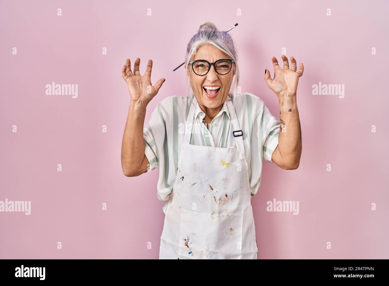 Middle age woman with grey hair wearing artist look celebrating mad and ...