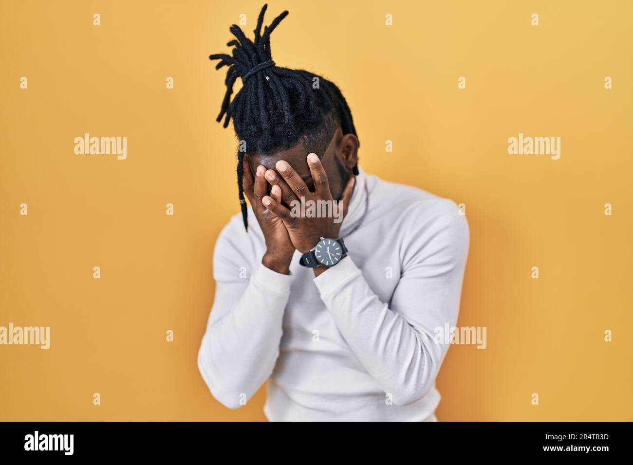 African man with dreadlocks wearing turtleneck sweater over yellow ...
