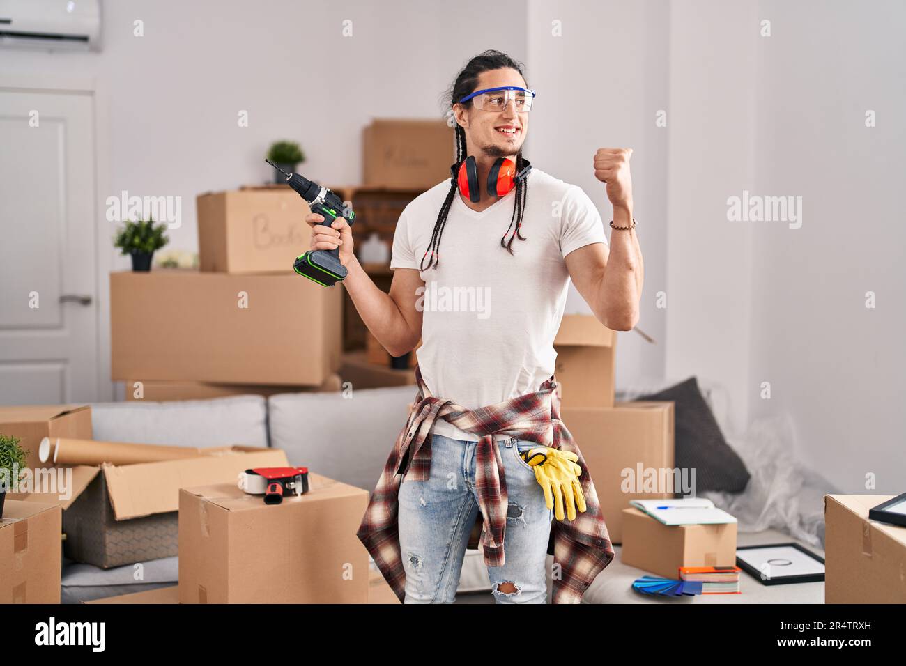 Hispanic man with long hair holding screwdriver at new home pointing ...