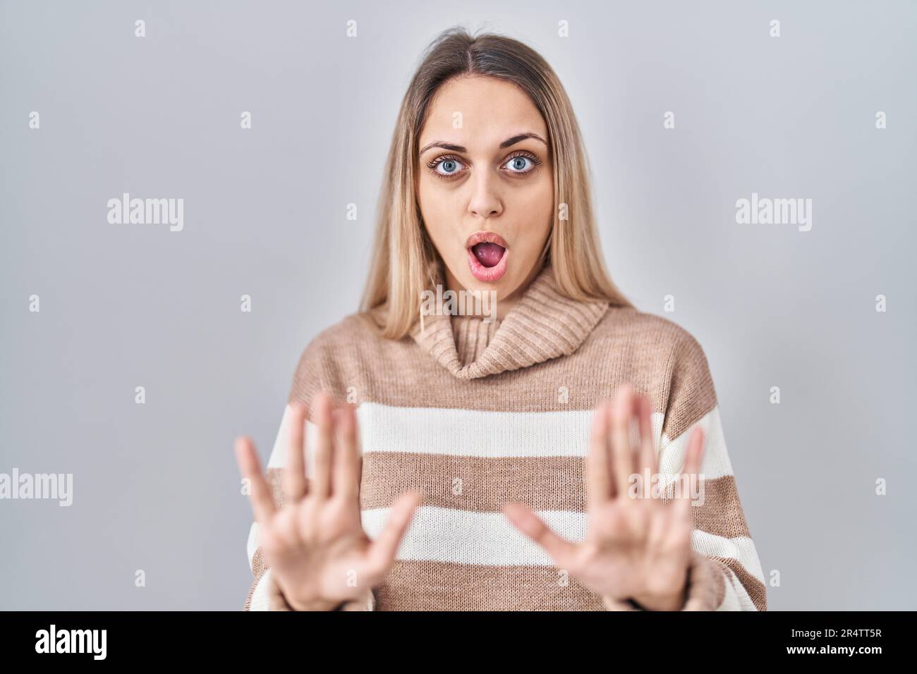 Young blonde woman wearing turtleneck sweater over isolated background ...