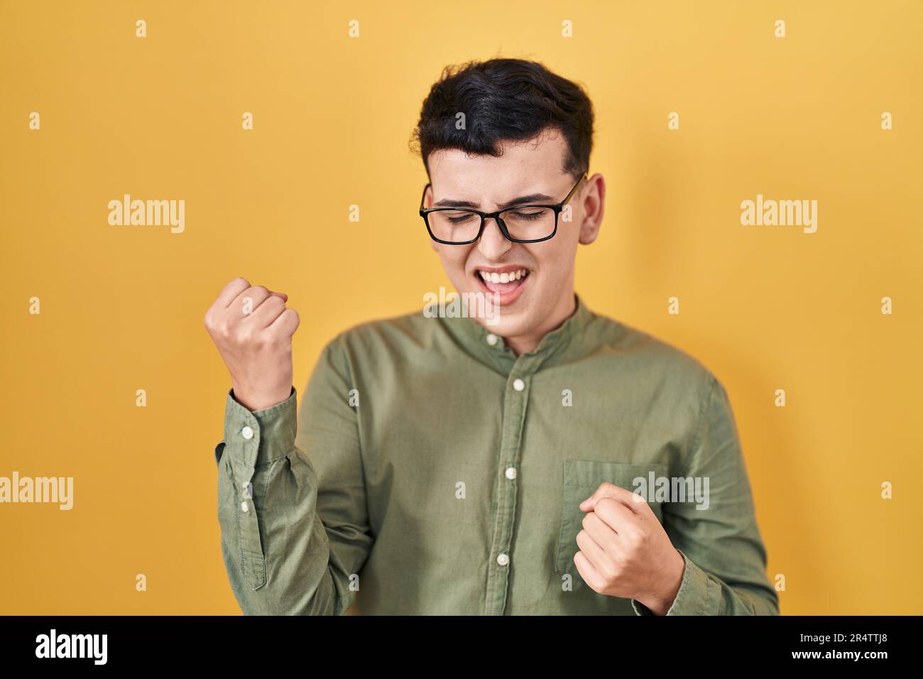 Non binary person standing over yellow background very happy and ...
