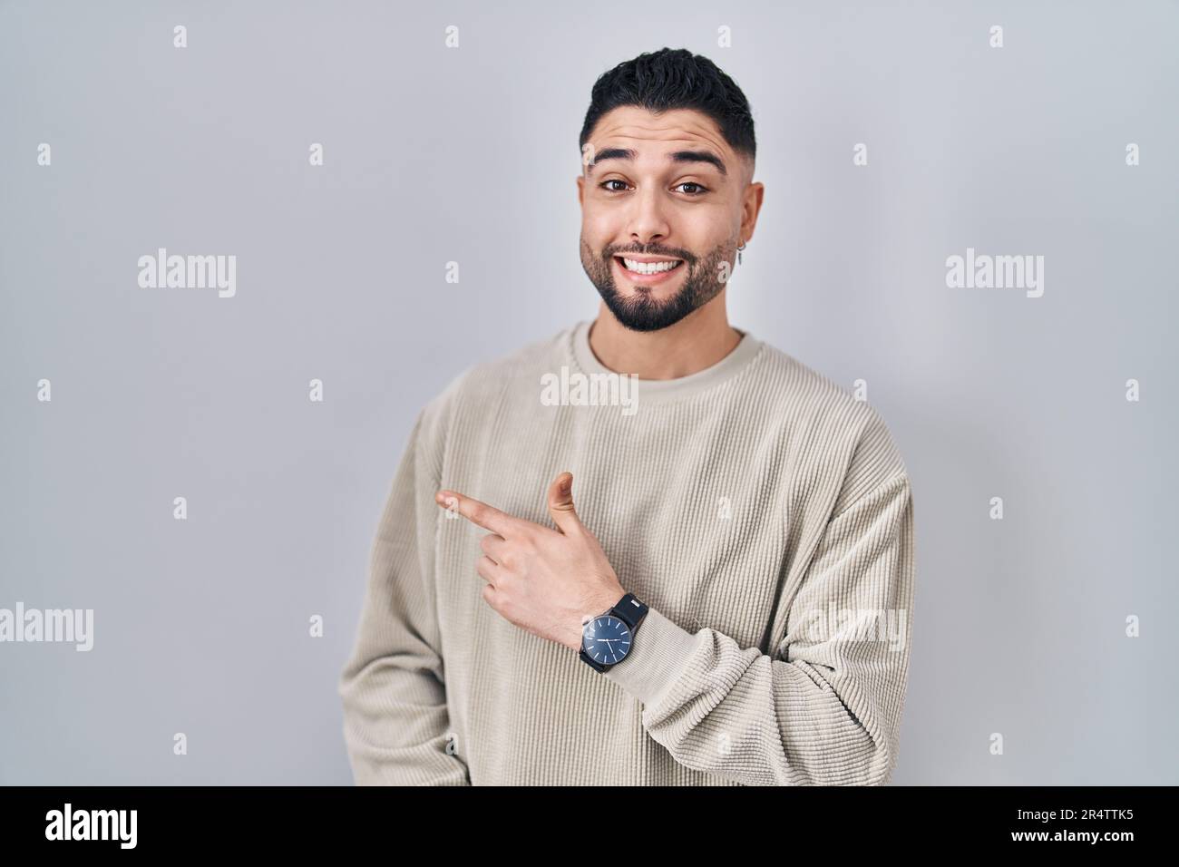 Young handsome man standing over isolated background pointing aside ...