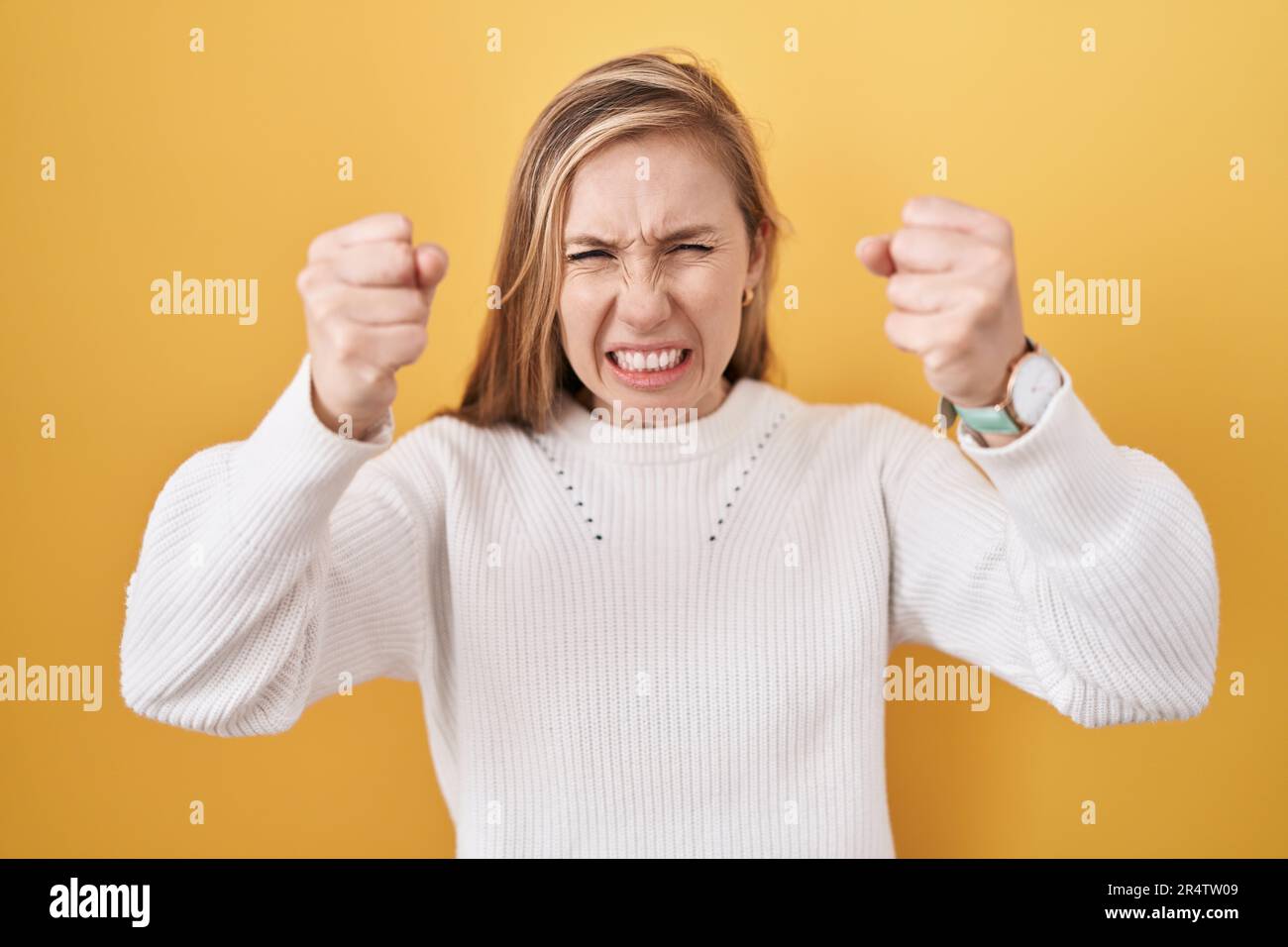 Young caucasian woman wearing white sweater over yellow background ...