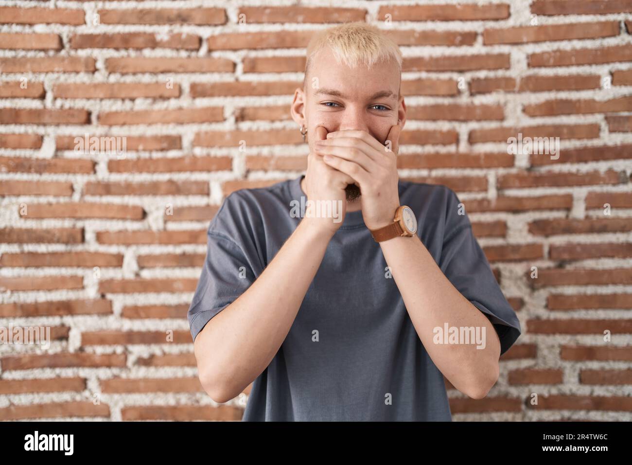 Young caucasian man standing over bricks wall laughing and embarrassed ...