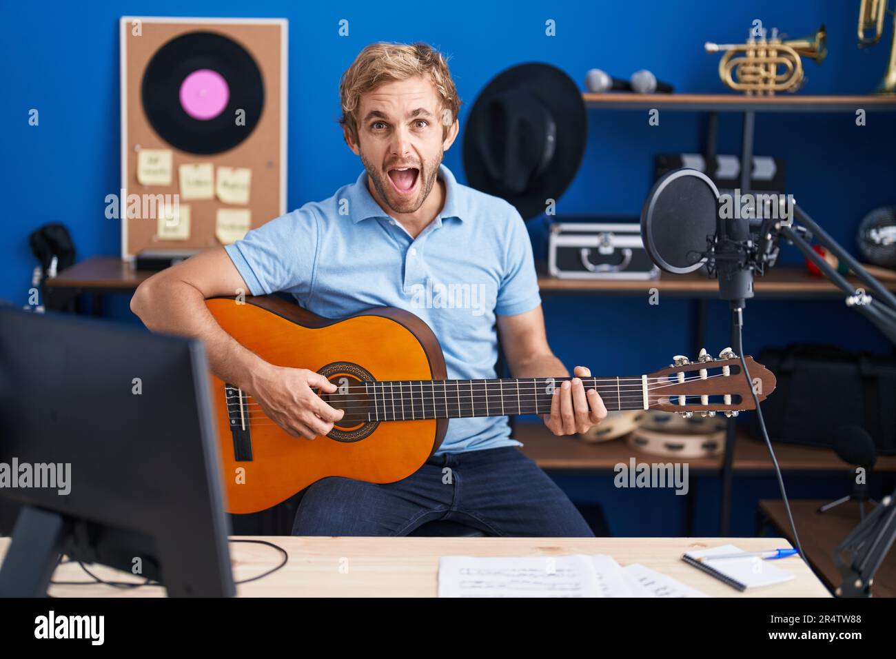 Caucasian man playing classic guitar at music studio angry and mad ...