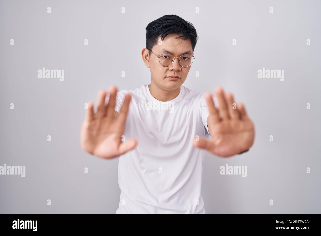 Young asian man standing over white background doing frame using hands ...
