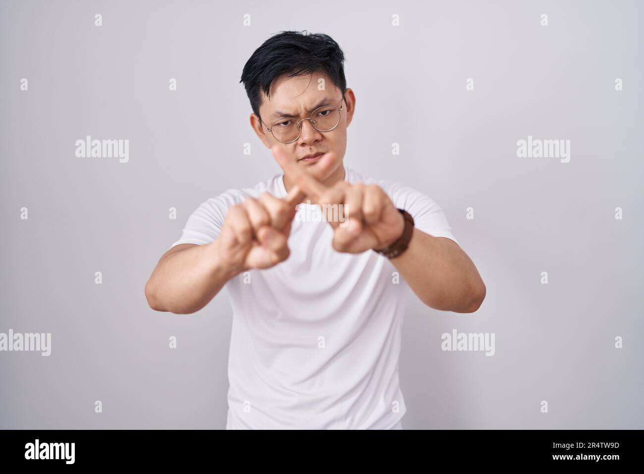 Young asian man standing over white background rejection expression ...