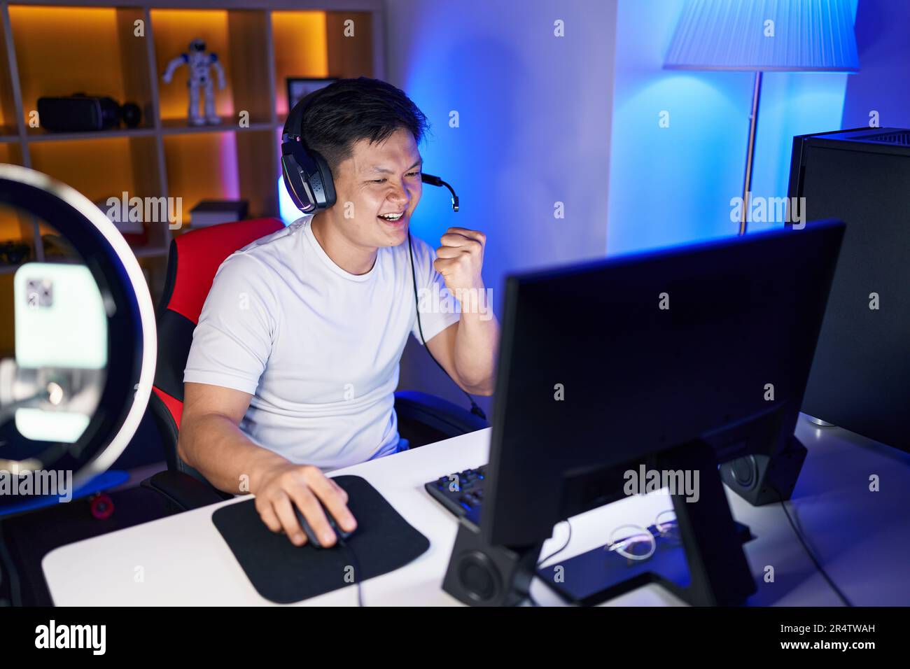 Young chinese man streamer playing video game with winner expression at ...