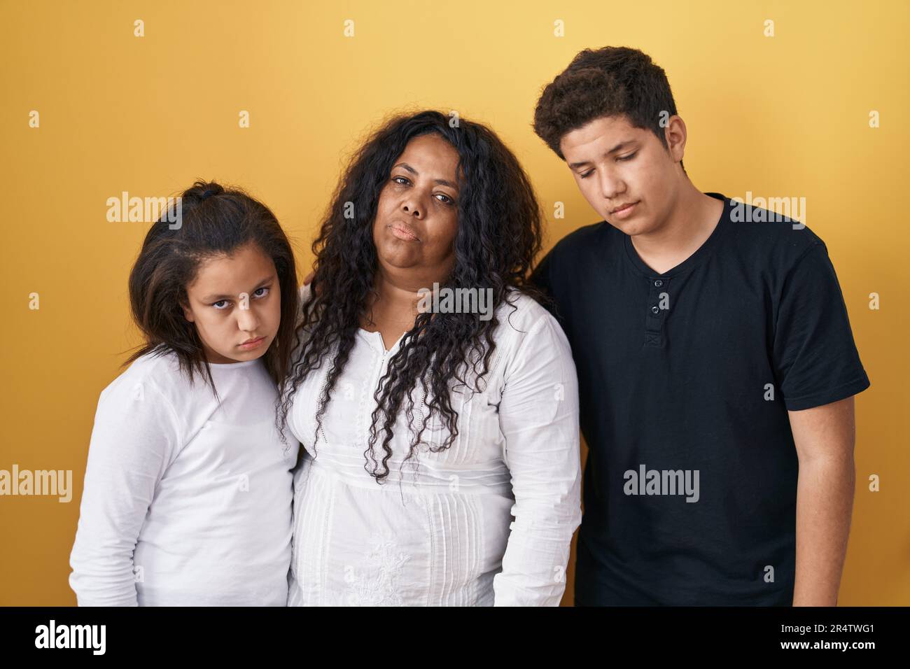 Family of mother, daughter and son standing over yellow background ...