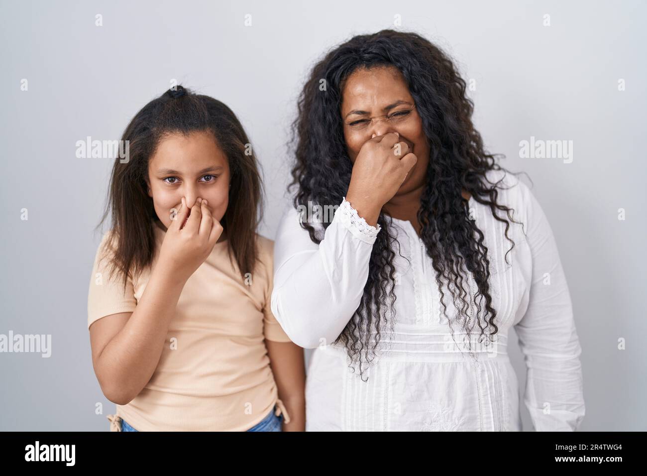 Mother and young daughter standing over white background smelling ...