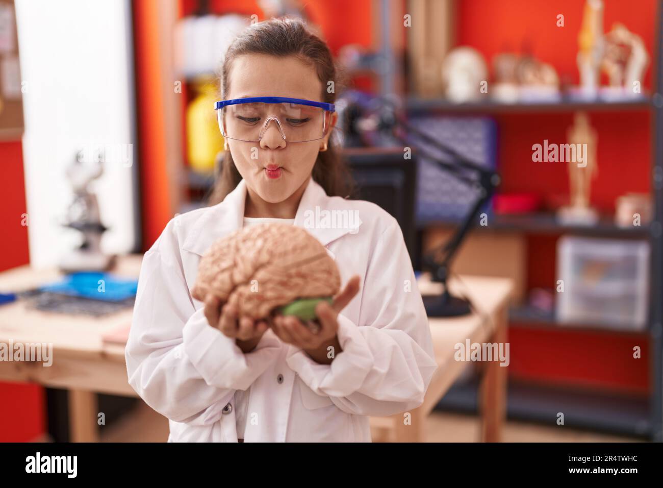 Little hispanic girl holding brain at science class at school making ...
