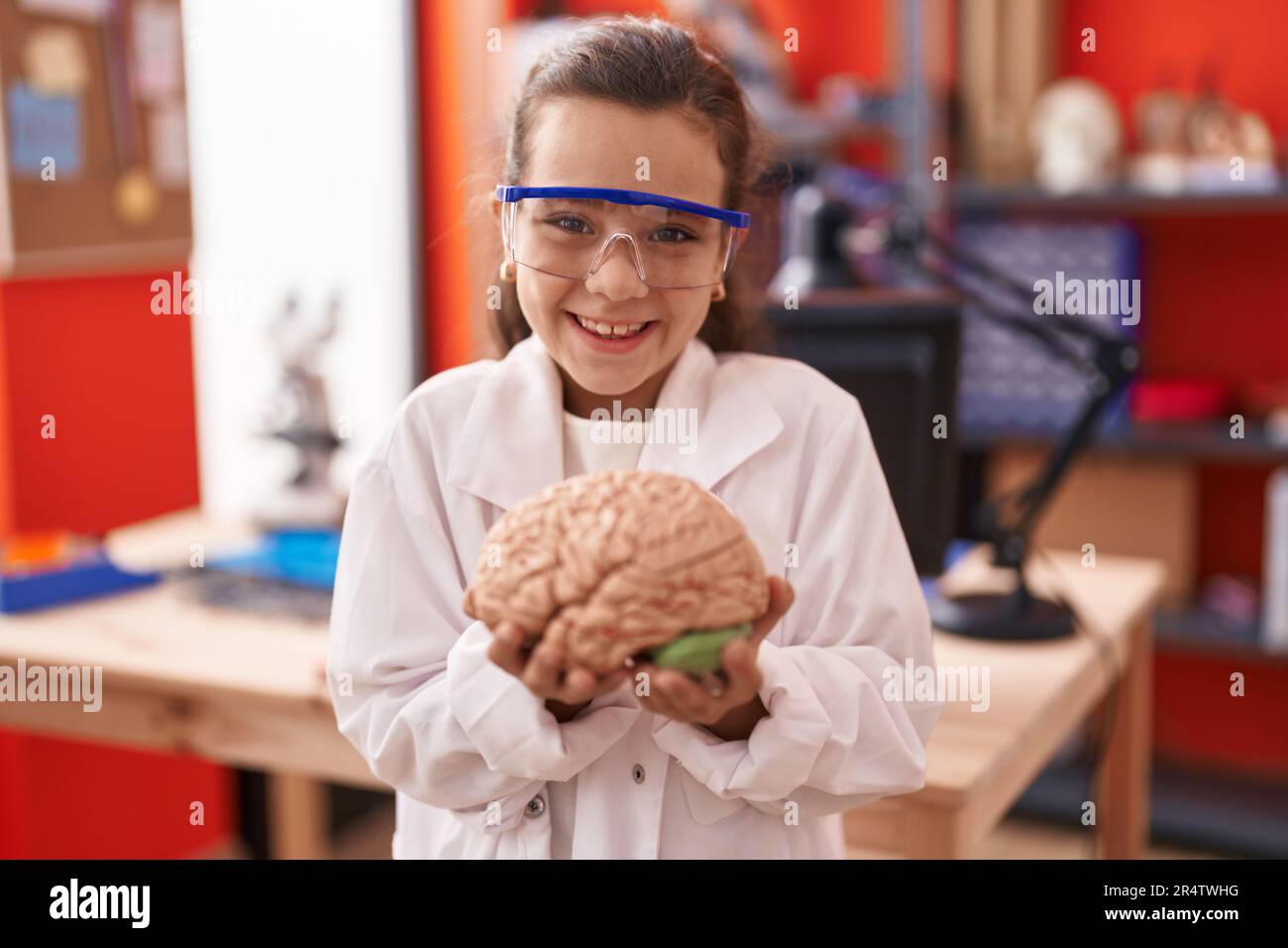 Little hispanic girl holding brain at science class at school smiling ...