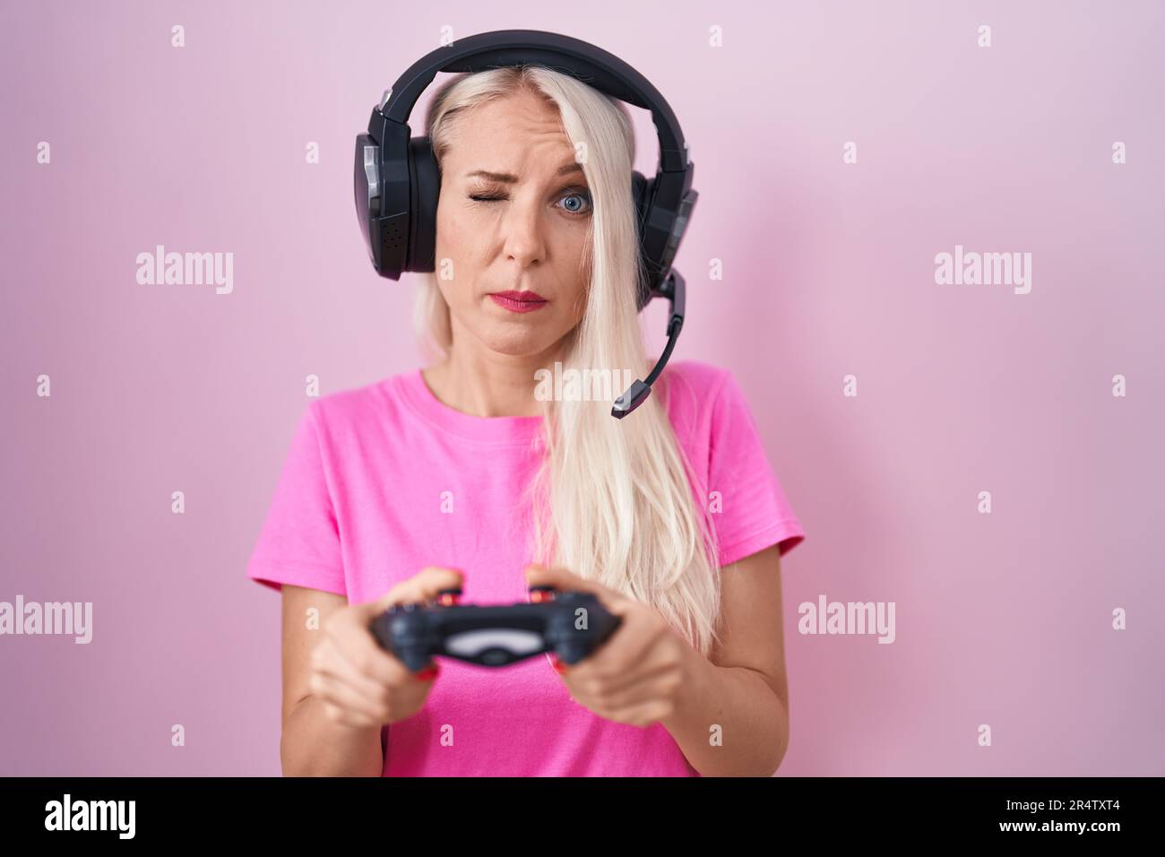 Caucasian woman playing video game holding controller skeptic and ...