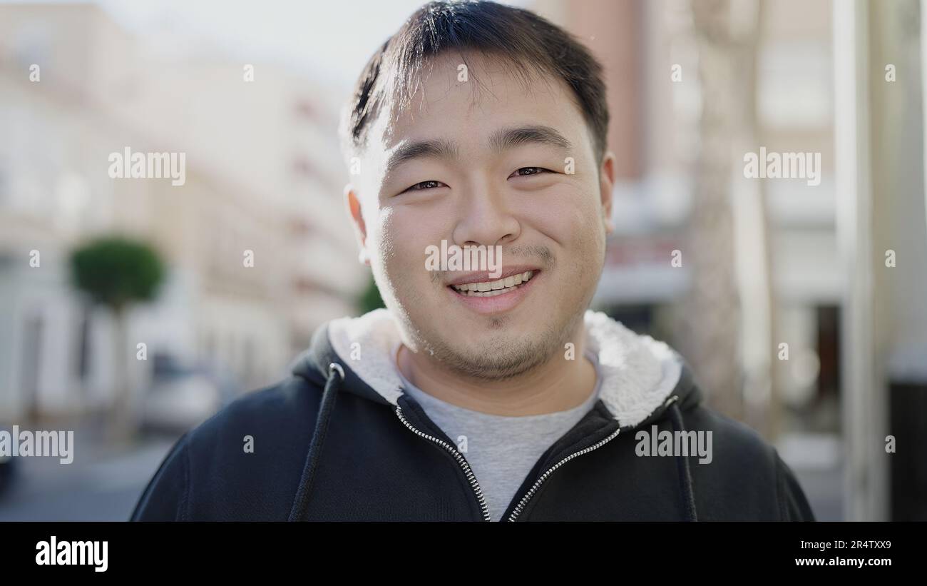 Young chinese man smiling confident standing at street Stock Photo - Alamy