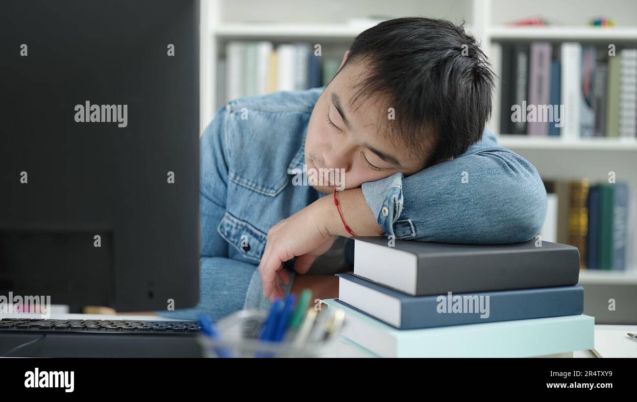 Young chinese man student sleeping on books at library university Stock ...