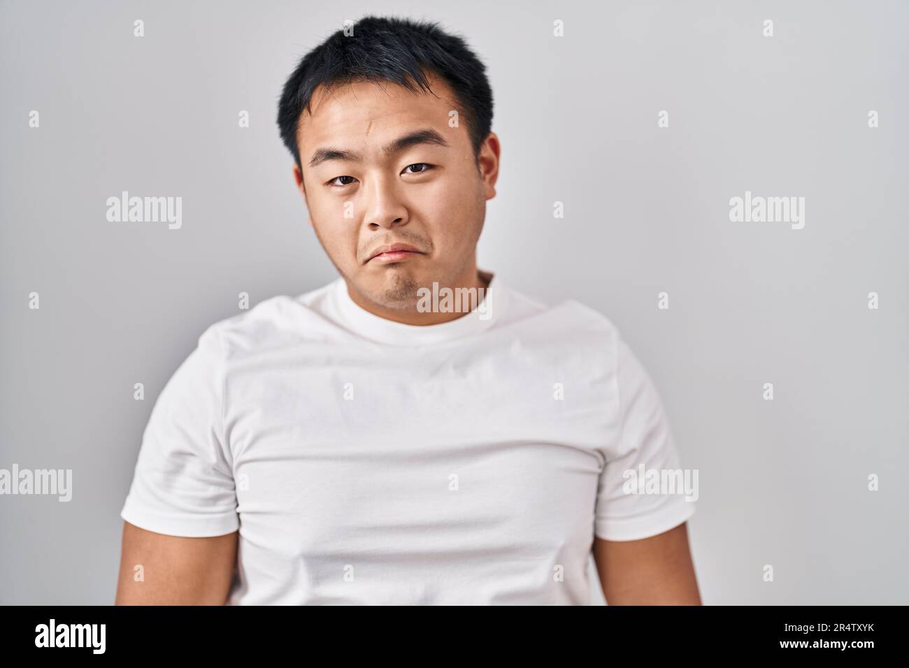 Young chinese man standing over white background depressed and worry ...