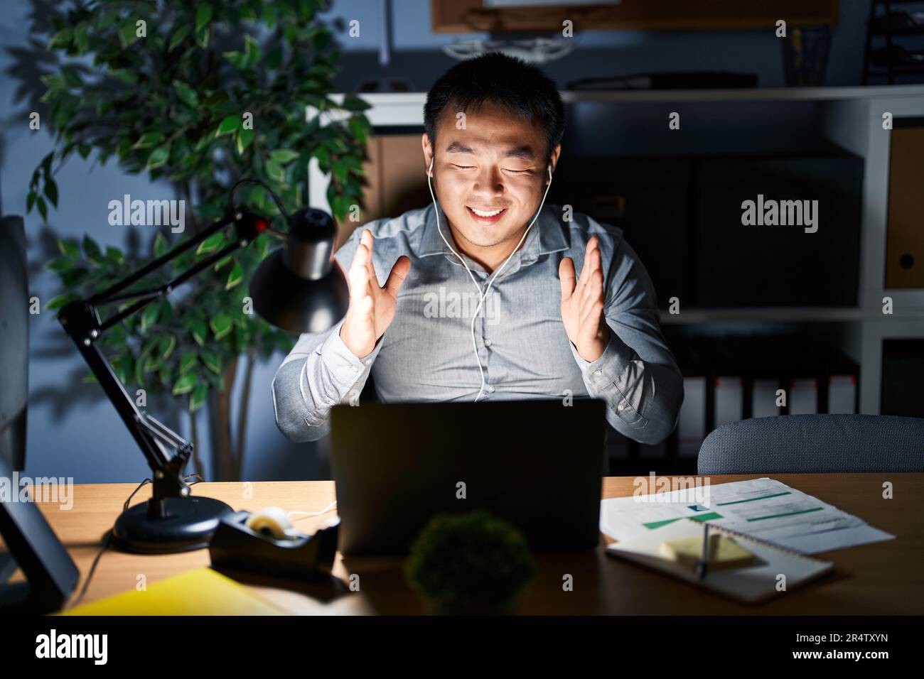 Young chinese man working using computer laptop at night celebrating ...